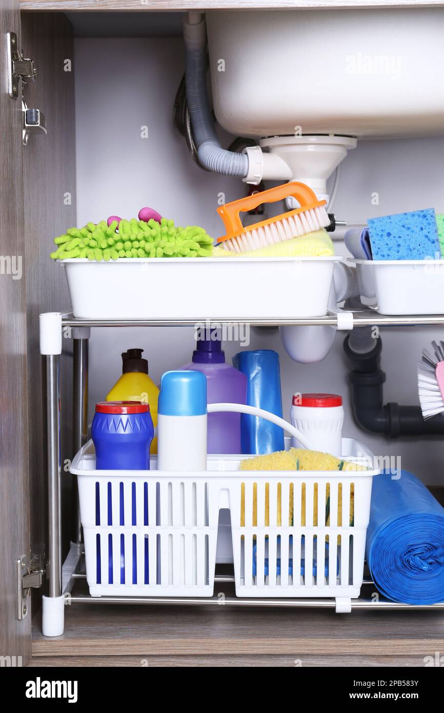 Open under sink cabinet with different cleaning supplies in kitchen ...