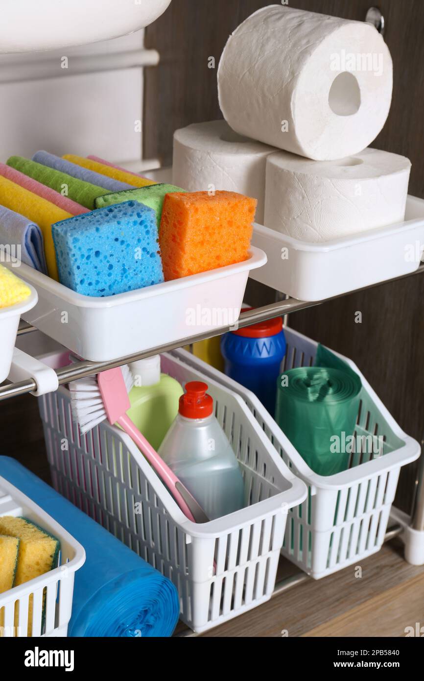Open under sink cabinet with different cleaning supplies in kitchen ...