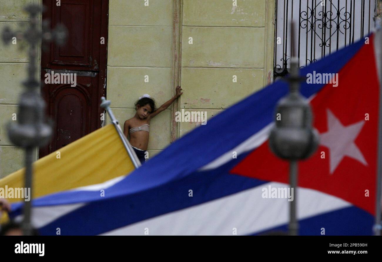 A girl watches a religious procession as a Cuban flag waves in Havana ...