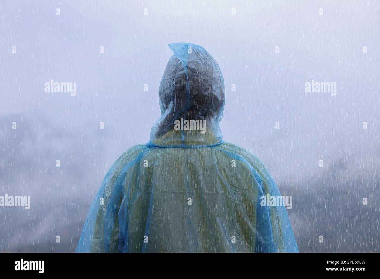 Woman in raincoat enjoying mountain landscape under rain, back view ...