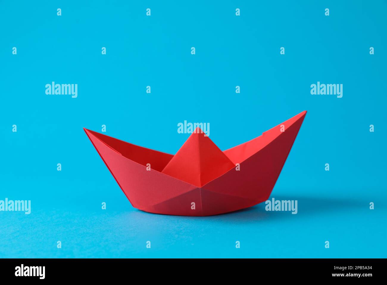 Handmade red paper boat on light blue background. Origami art Stock ...