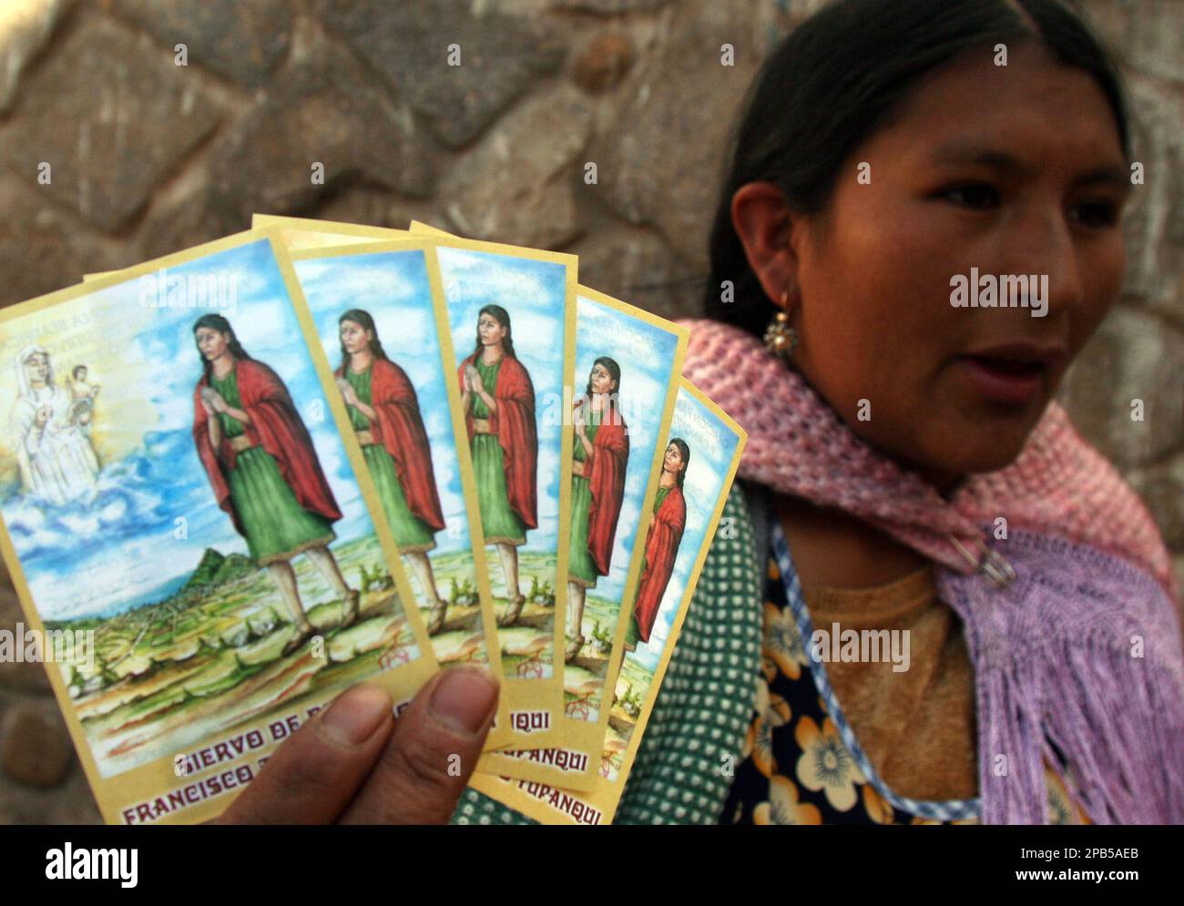 An Aymara woman holds images of indigenous priest Francisco Tito ...