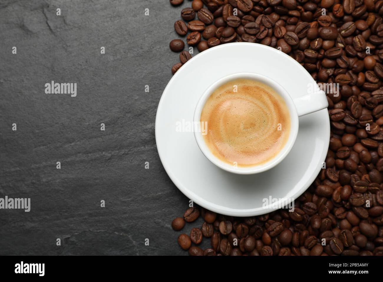 Cup of hot drink and beans on black table, top view with space for text ...