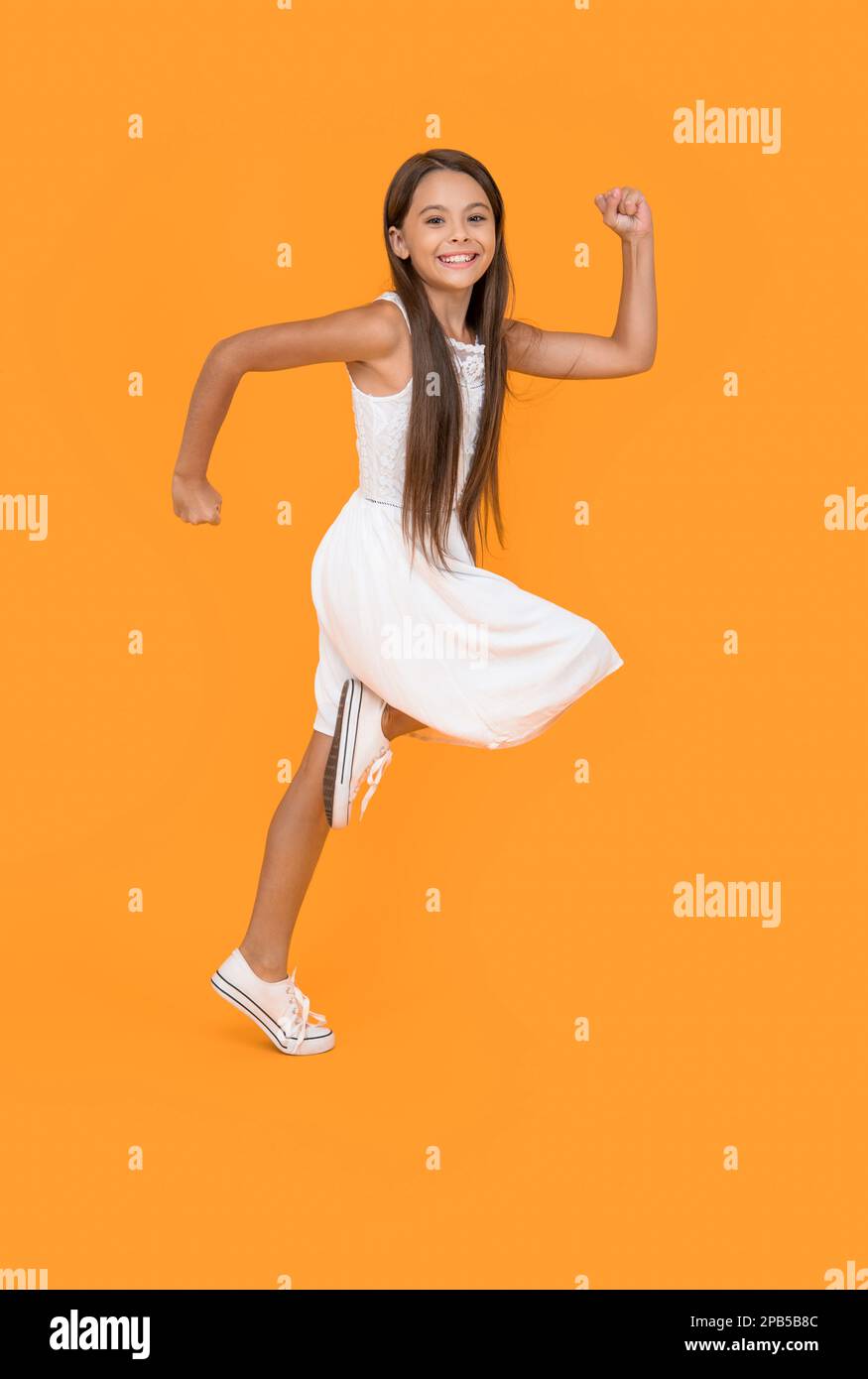 happy teen girl in white dress running on yellow background Stock Photo ...