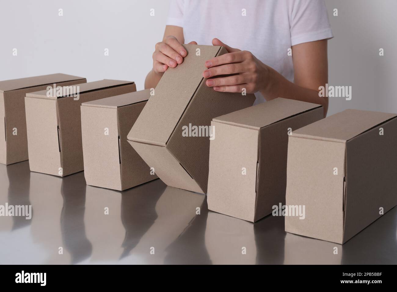 Woman folding cardboard boxes at table, closeup. Production line Stock ...