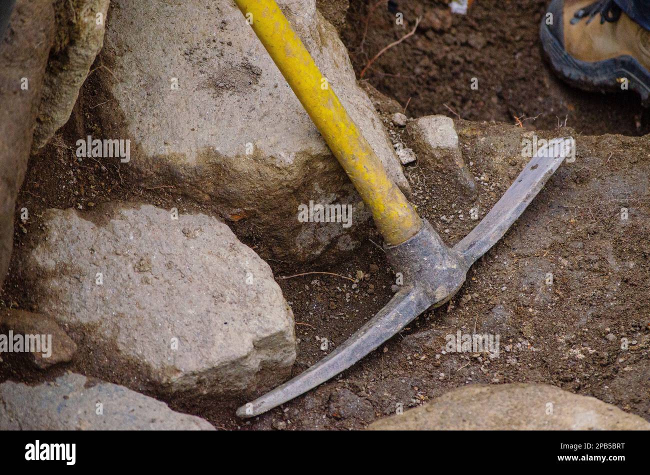 A yellow plastic-handled pick leaning against a wall during work at an ...
