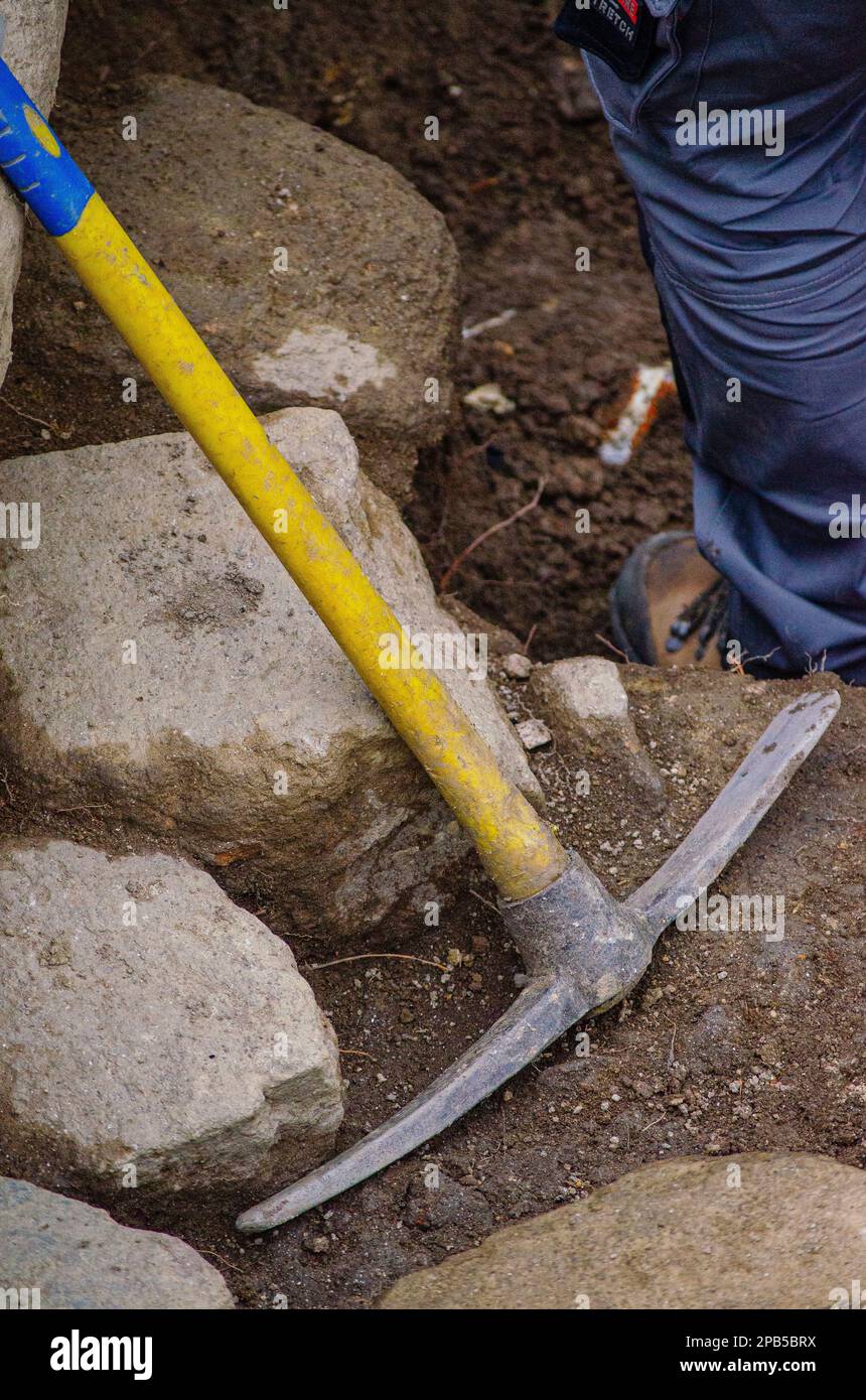 A plastic-handled pick leaning against a wall during work at an ...