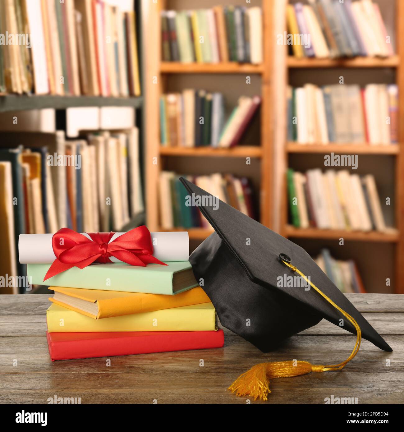 Graduation hat, books and diploma on wooden table in library Stock ...