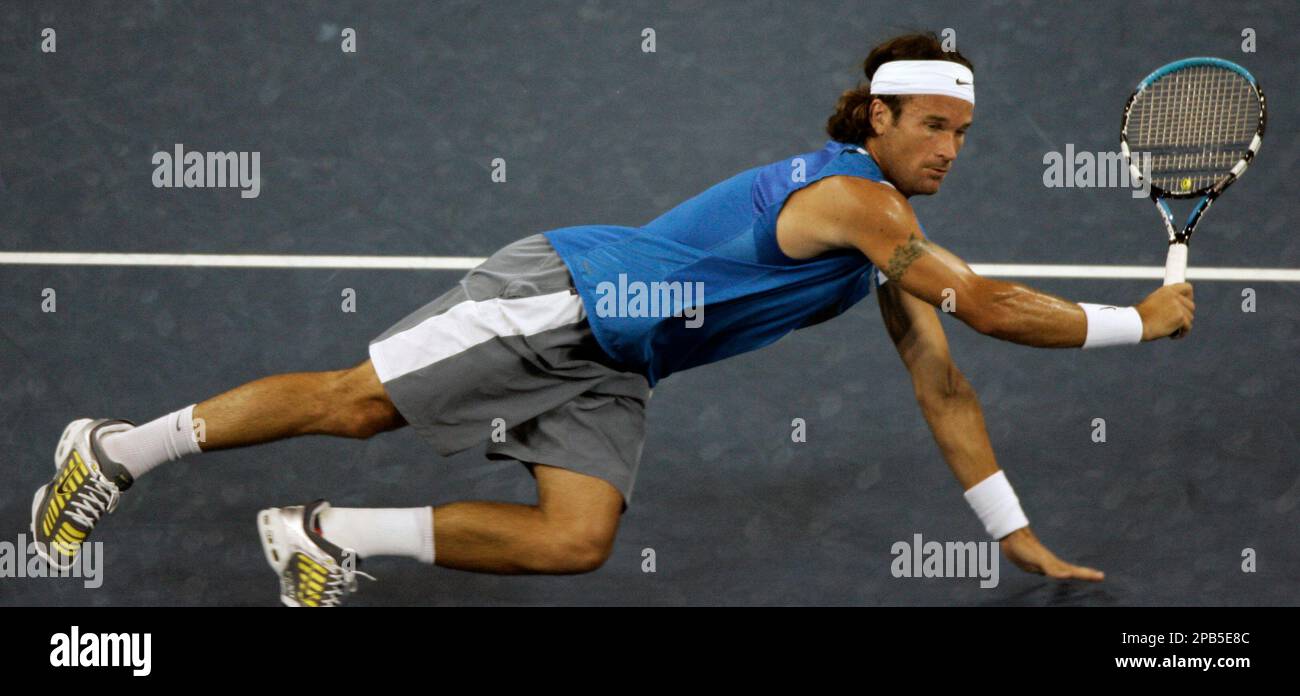 Carlos Moya of Spain falls as he attempt to return a shot to Novak ...