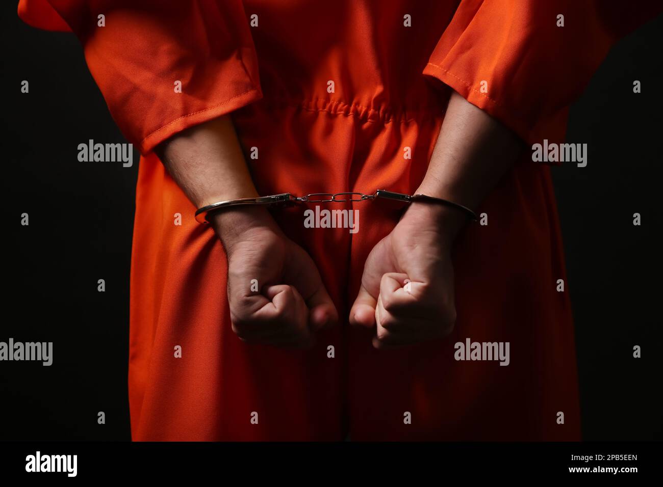Prisoner in jumpsuit with handcuffs on black background, closeup Stock ...