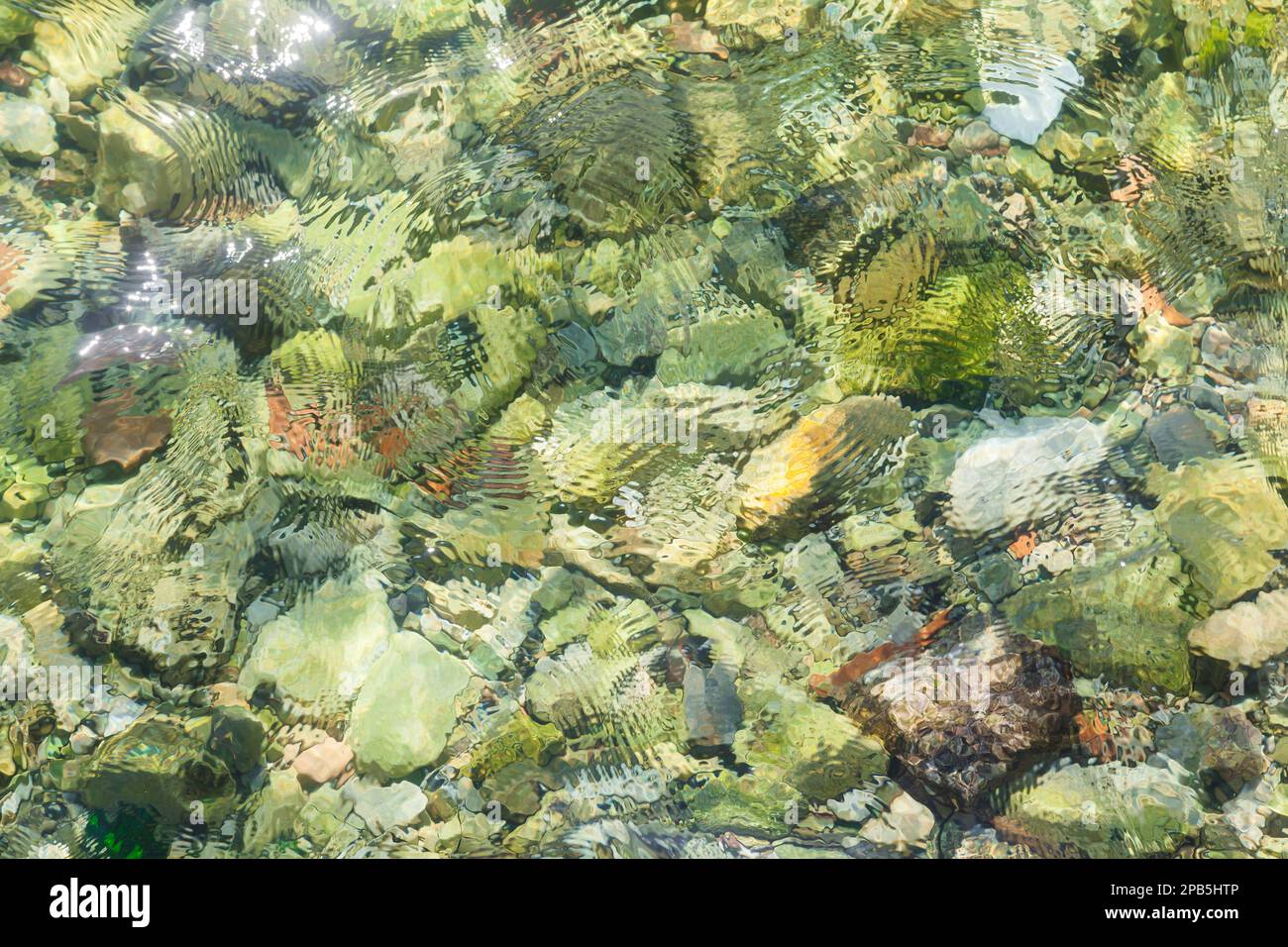 background texture of rippled water surface with pebble stones on the ...