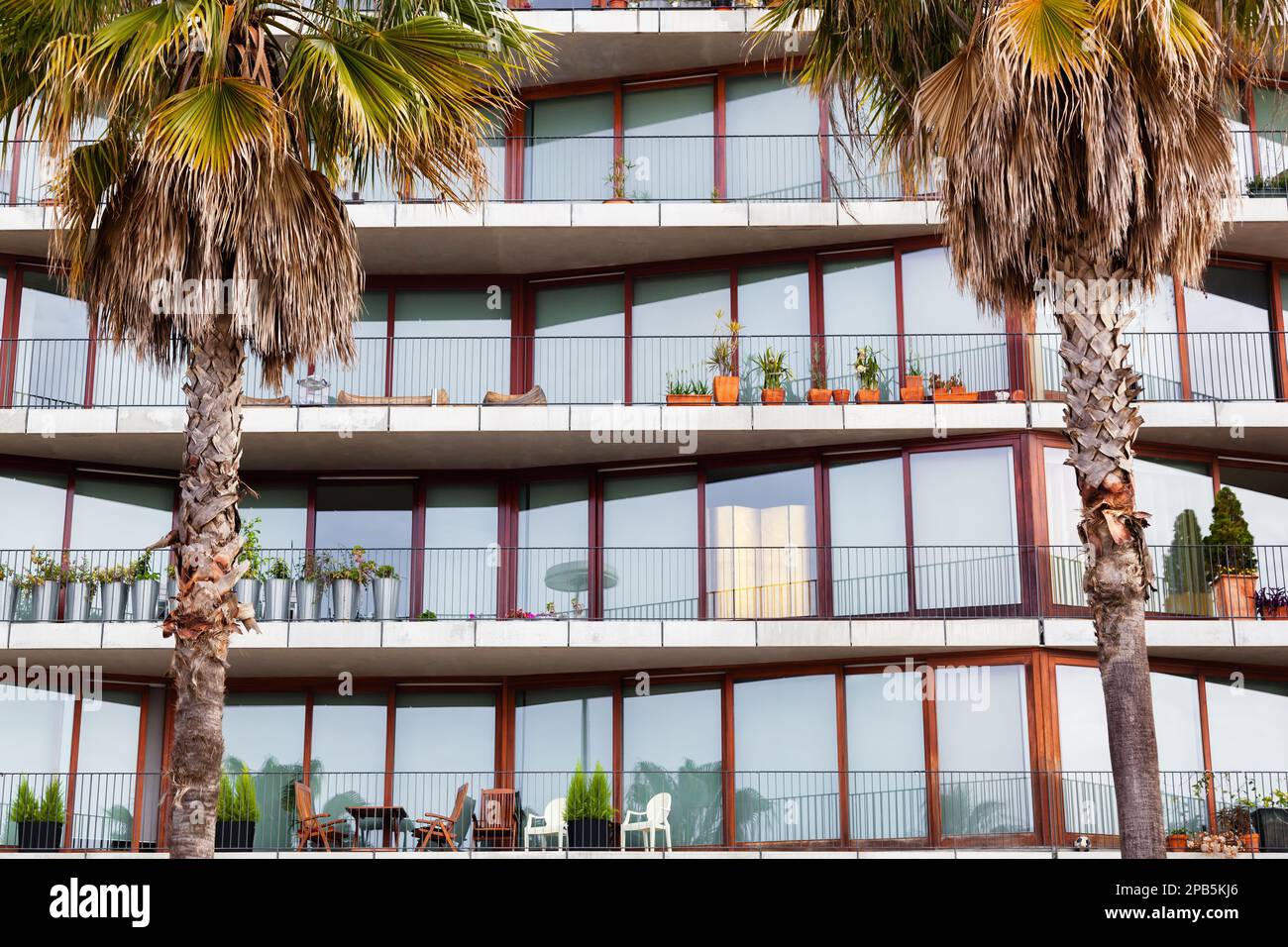 facade of a hotel with balconies and palm trees in front Stock Photo ...