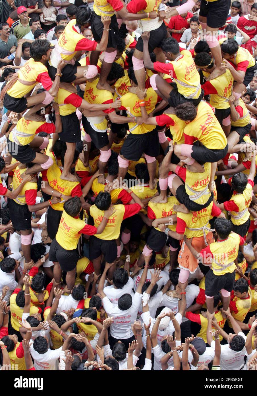 Hindu devotees climb on top of each other to form a human pyramid to ...