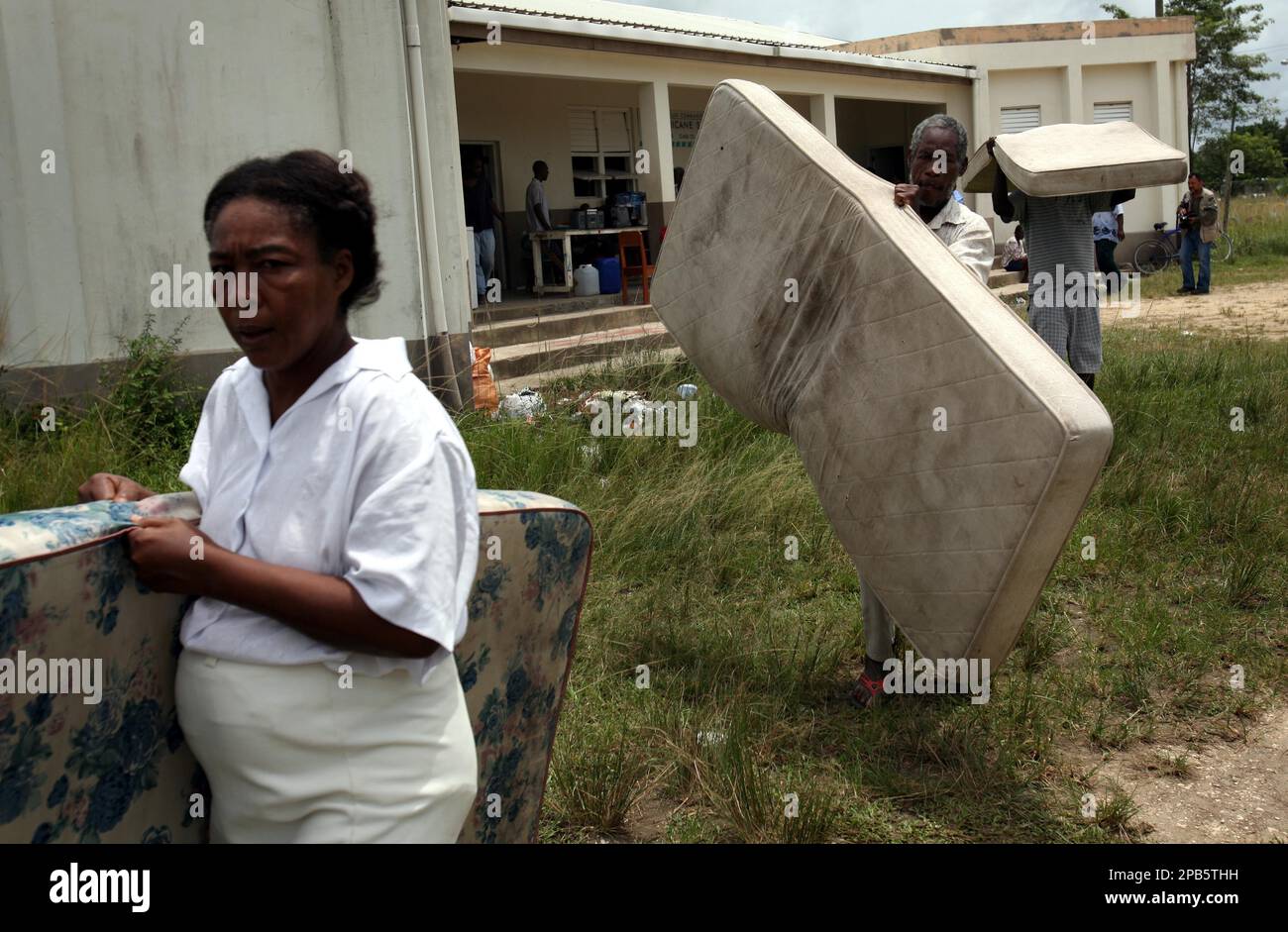 Belize residents carry government donated mattresses to dry in the sun ...