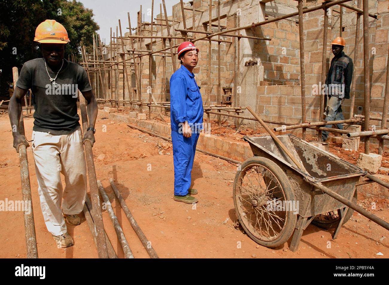 A Chinese foreman looks on as laborers work on the construction of ...