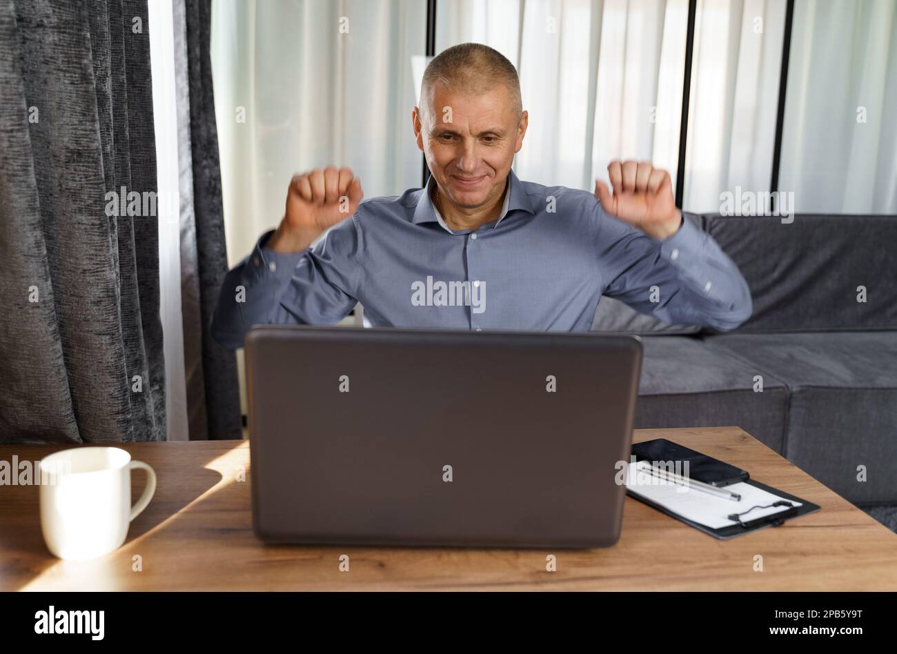 A businessman working at a computer rejoices in a perfect successful ...