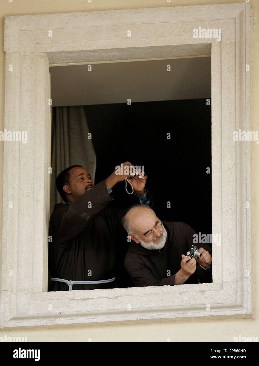 Two friars take picture from a window as they wait for the arrival of ...