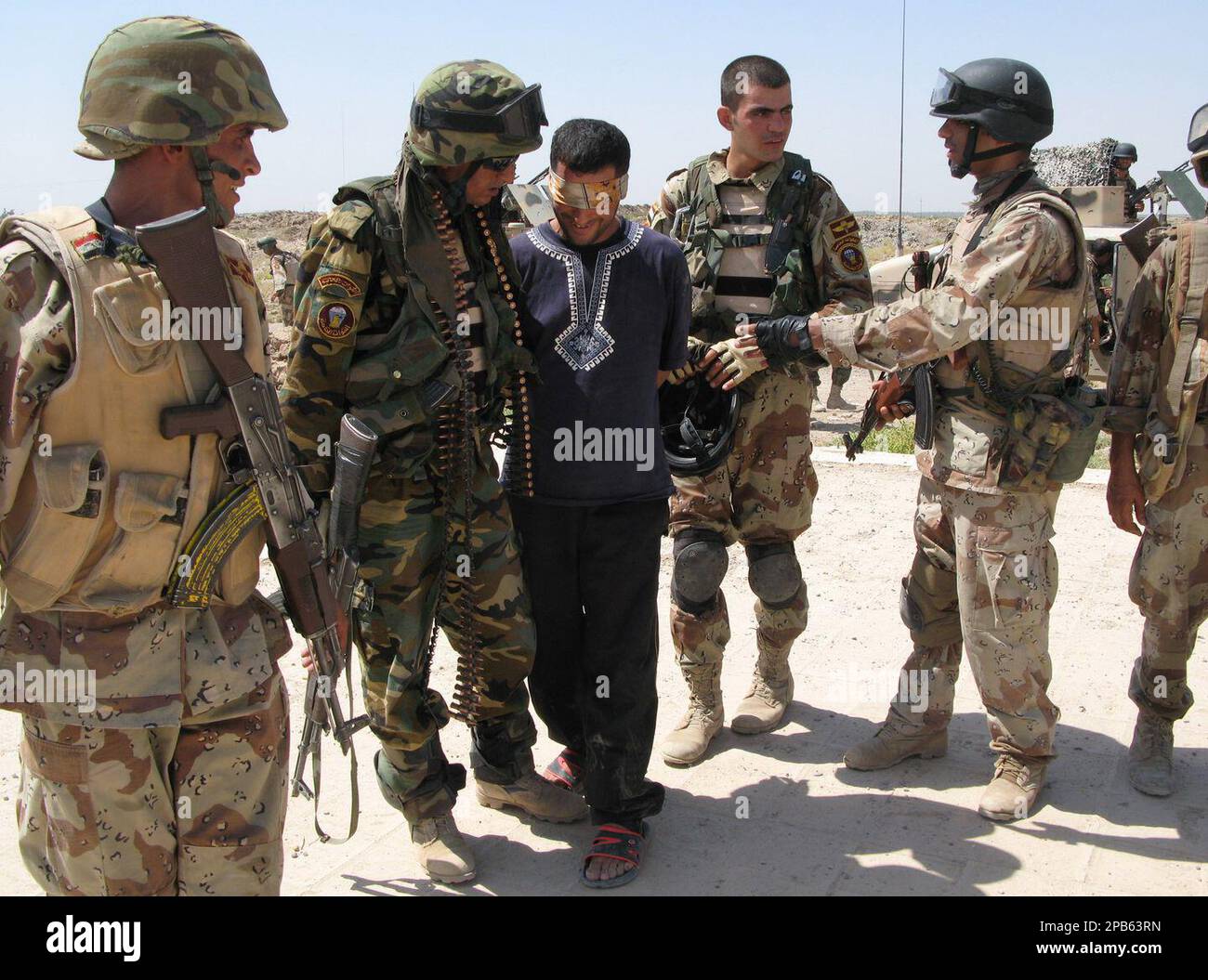 Iraqi soldiers guard a detainee arrested in the city of Baqouba, some ...