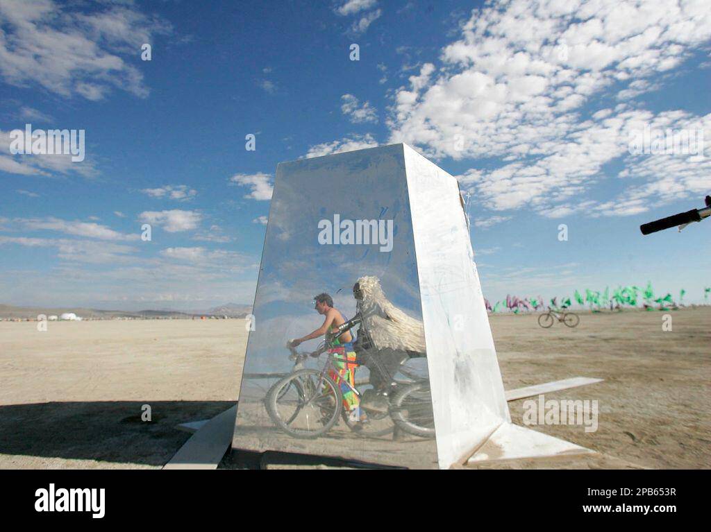 Burning Man participants are reflected in an art piece on the playa of ...