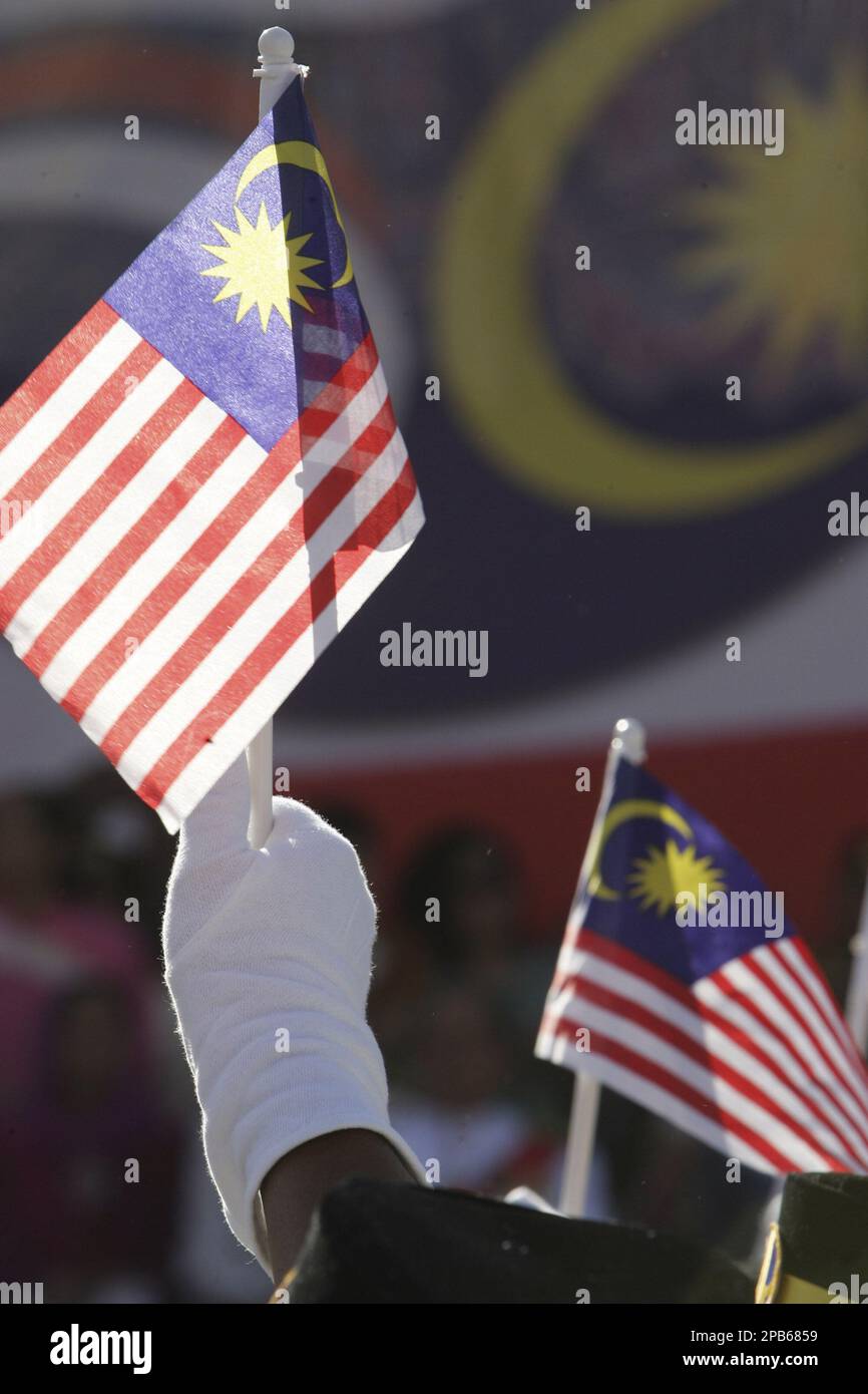 Malaysian performers wave national flags during a parade at the ...