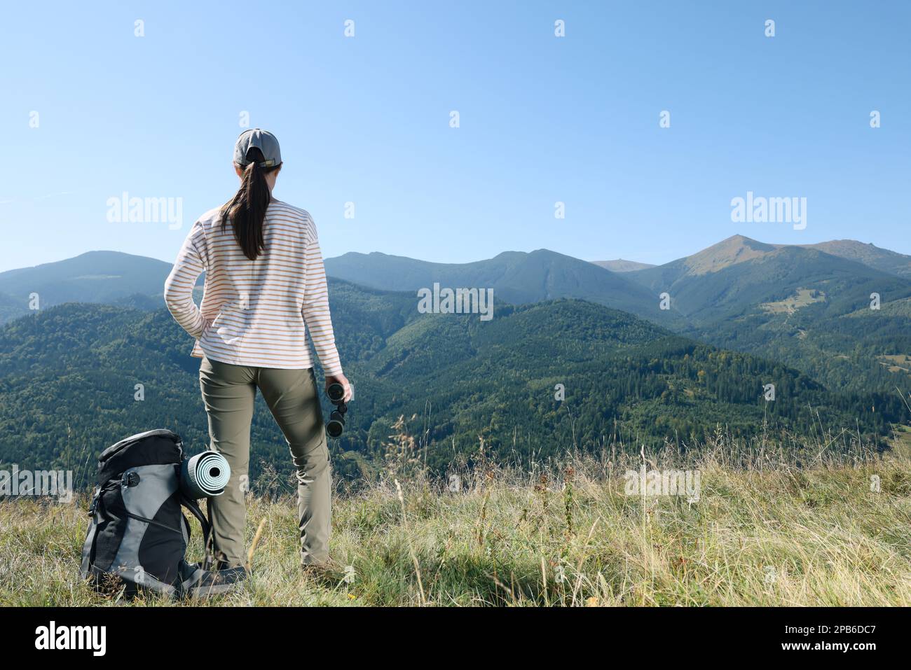 Tourist with hiking equipment and binoculars in mountains, back view ...
