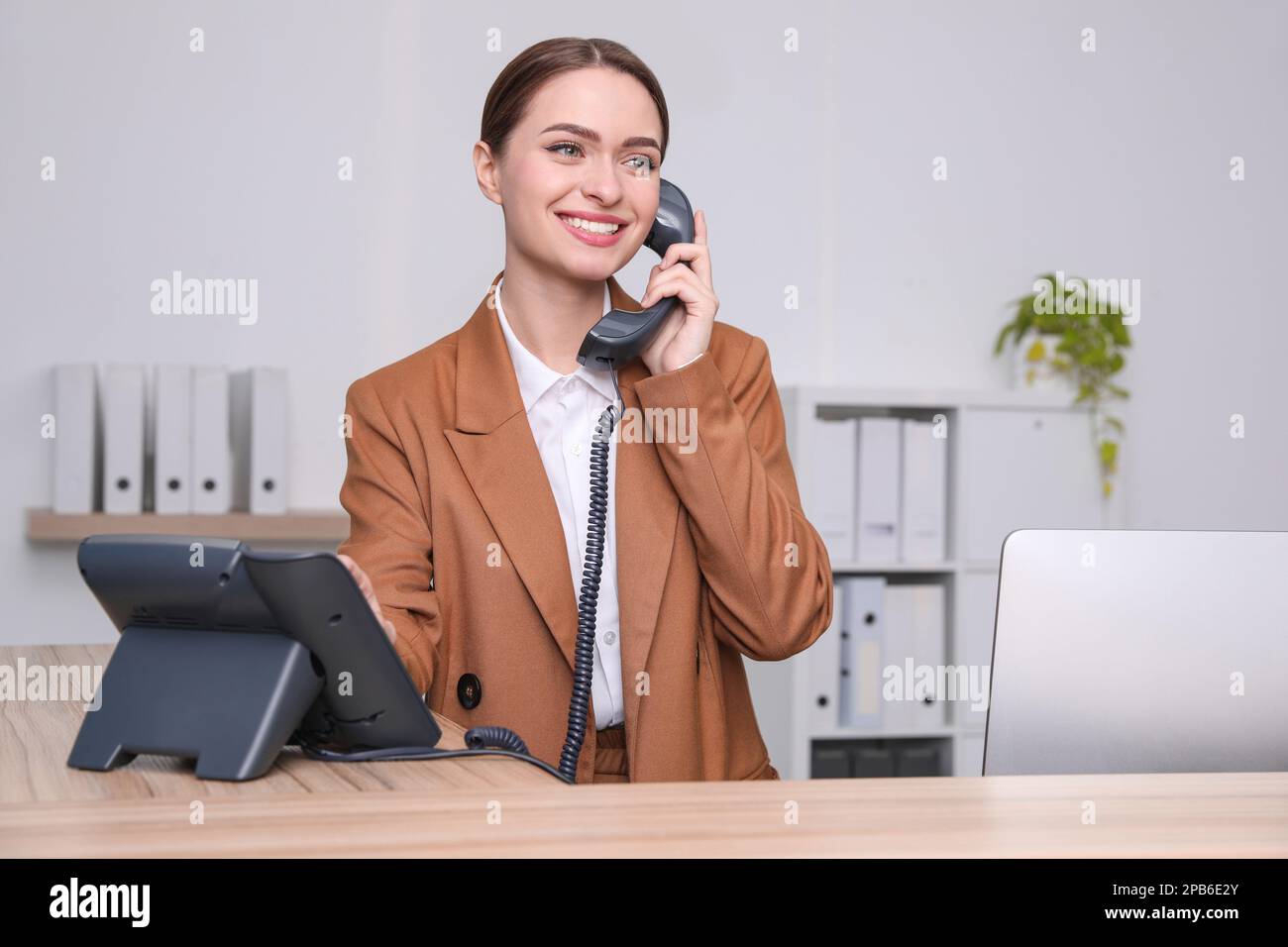 Female receptionist talking on phone at workplace Stock Photo - Alamy