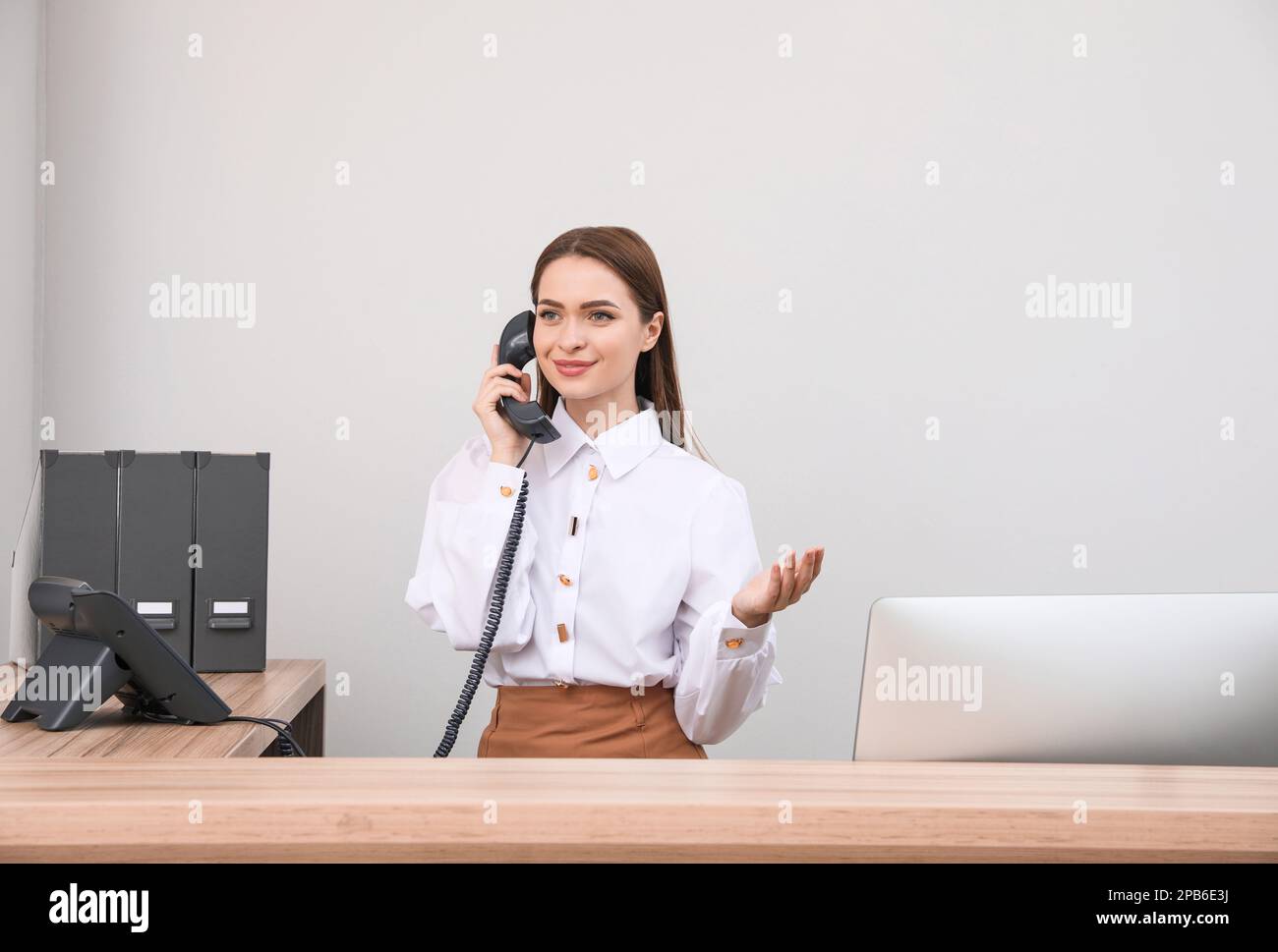Female receptionist talking on phone at workplace Stock Photo - Alamy