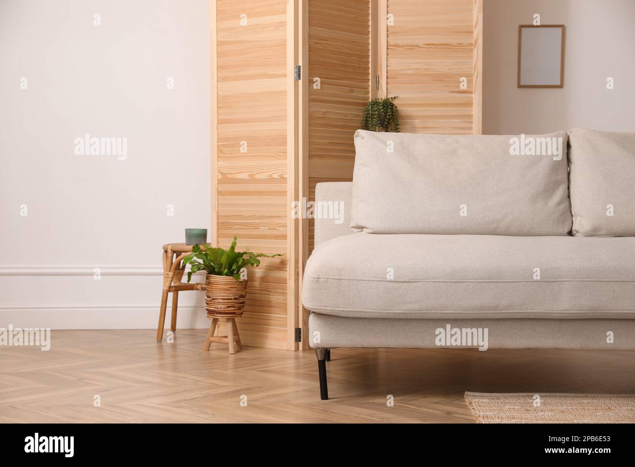 Stylish room with wooden folding screen and comfortable sofa near white ...