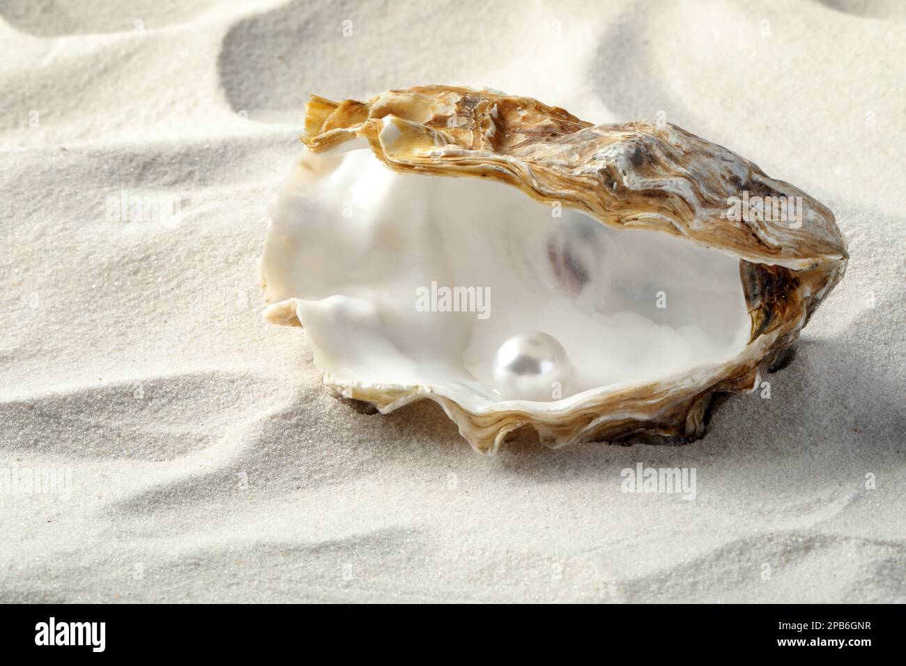 Open oyster with white pearl on sand Stock Photo - Alamy