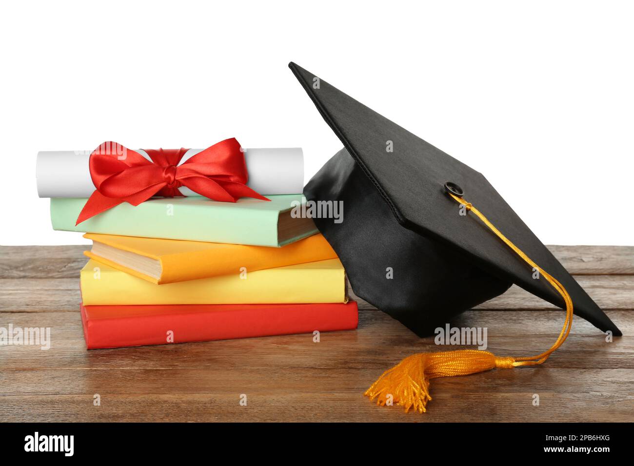 Graduation hat, books and diploma on wooden table against white ...