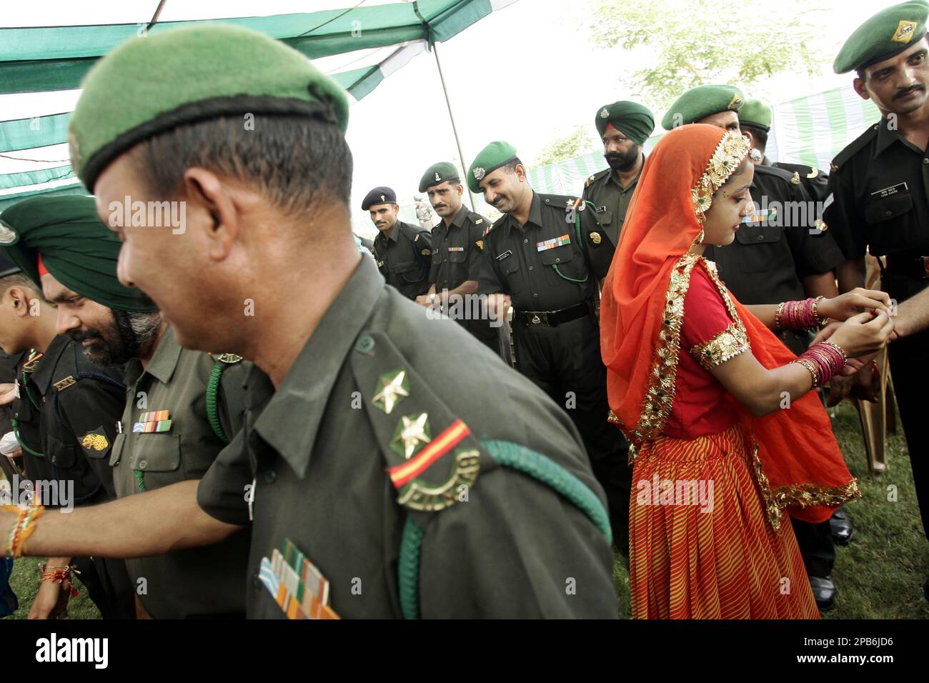 School girls tie 'Rakhis' or a colorful band on the wrists of the ...