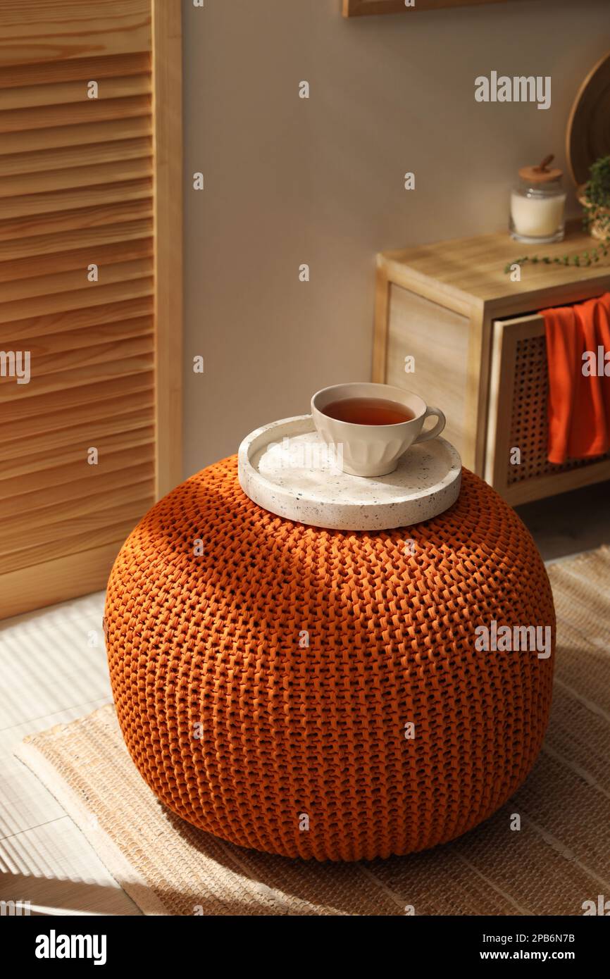 Tray with cup of tea on stylish comfortable pouf in room. Home design ...