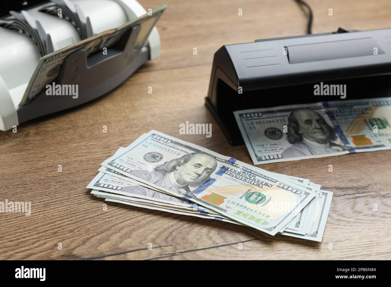 Modern currency detector with dollar banknotes on wooden table. Money ...