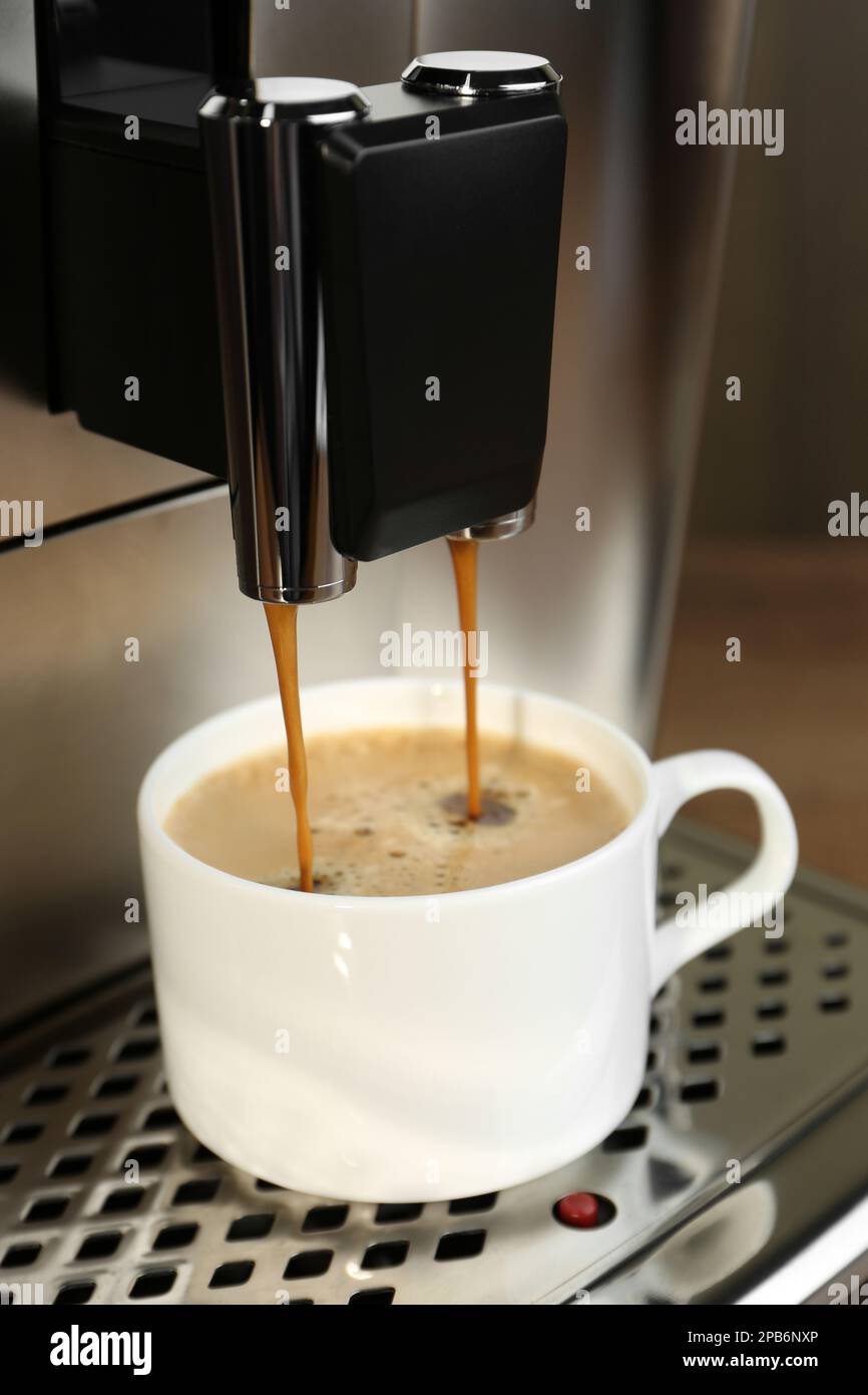 Modern espresso machine pouring coffee into cup on wooden background ...