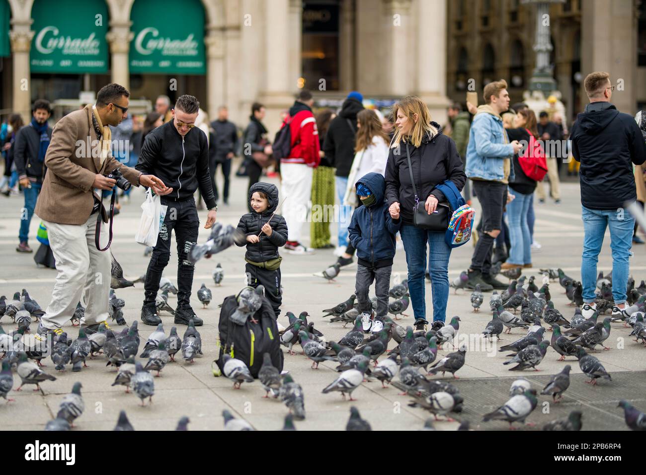 MILAN, ITALY - APRIL 2022: A group of people feeding the pigeons on the ...