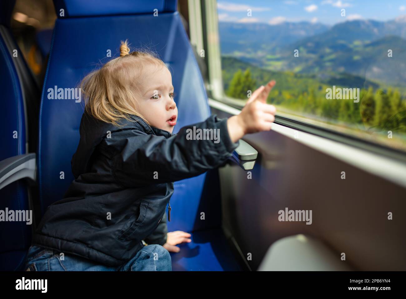 Toddler boy traveling by train. Little child sitting by the window in ...