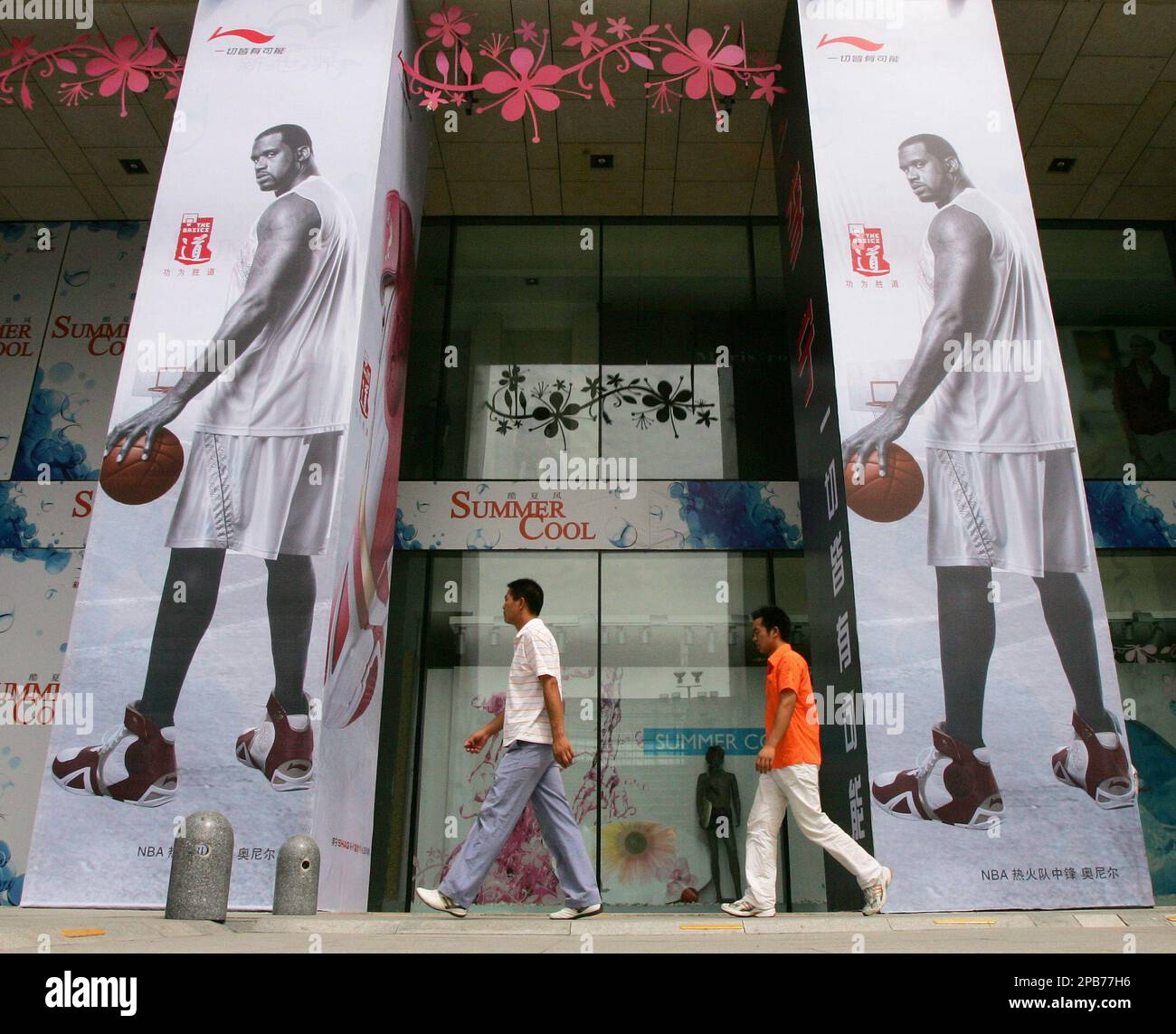 Two men walk past billboard advertisements for Chinese shoe and ...