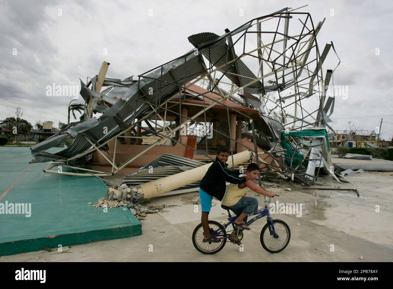 Two boys ride a bicycle past the rubble of a destroyed building in ...