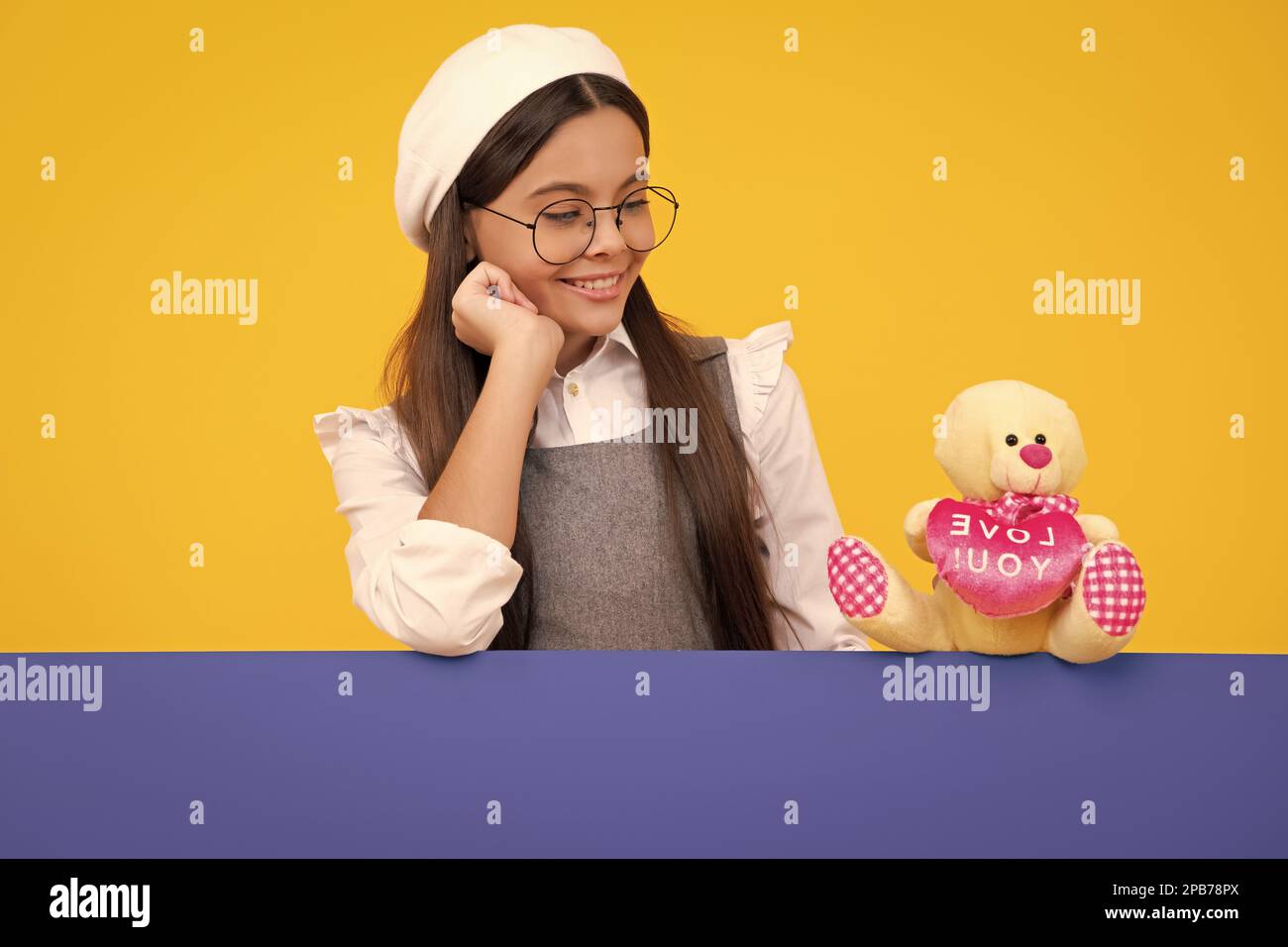 Teenager girl 12, 13, 14 year old hold soft toy for birthday on yellow ...