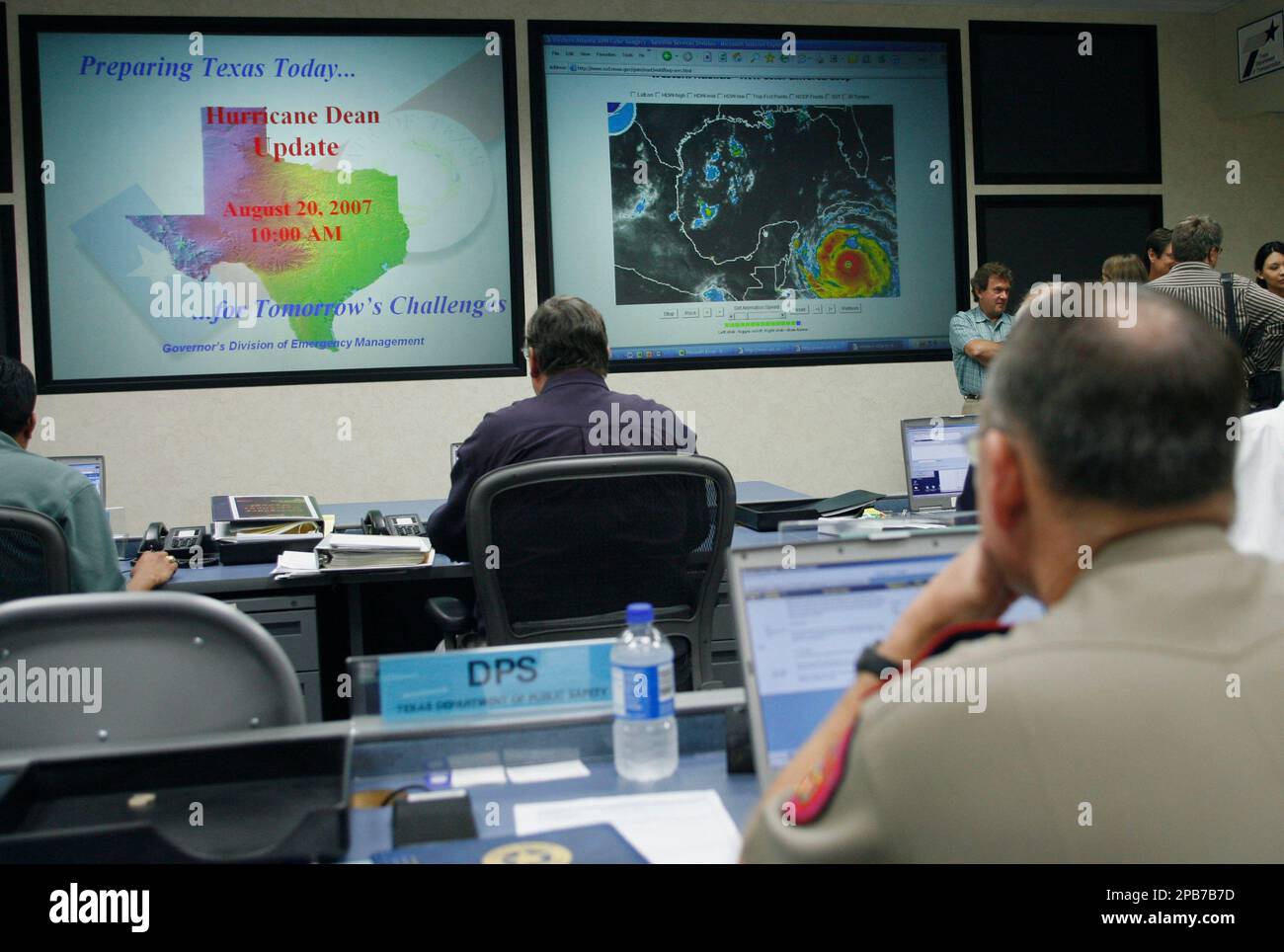 Workers in the State Operations Center are shown before a briefing ...