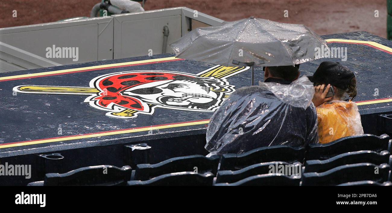 A couple huddles under their umbrella behind the Pittsburgh Pirates ...