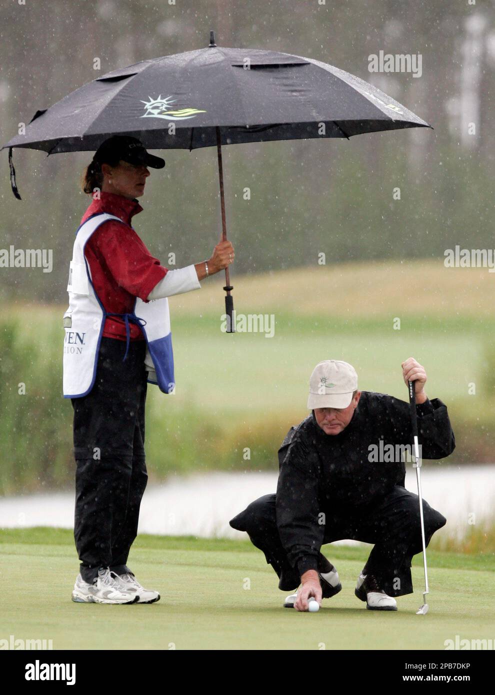 Caddie Sandy Jones, left, keeps the pouring rain off Tom Kite as he ...