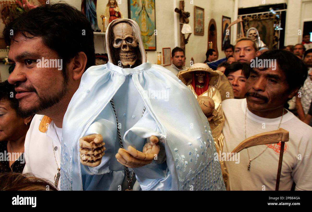 A man holds a skeletal figure representing the folk saint known in ...