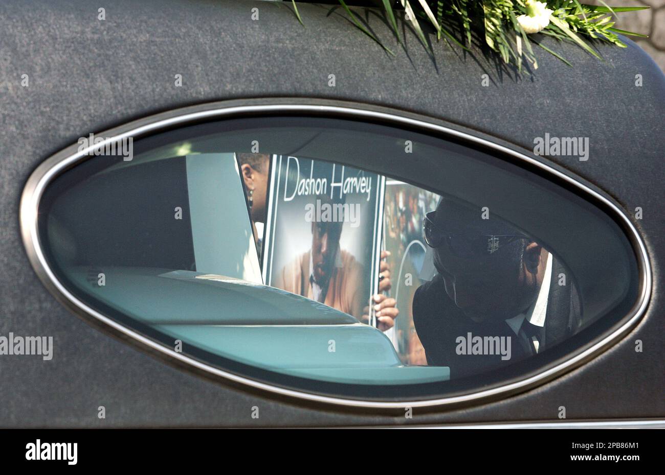 A person holds a poster of Dashon Harvey as the casket of Iofemi ...