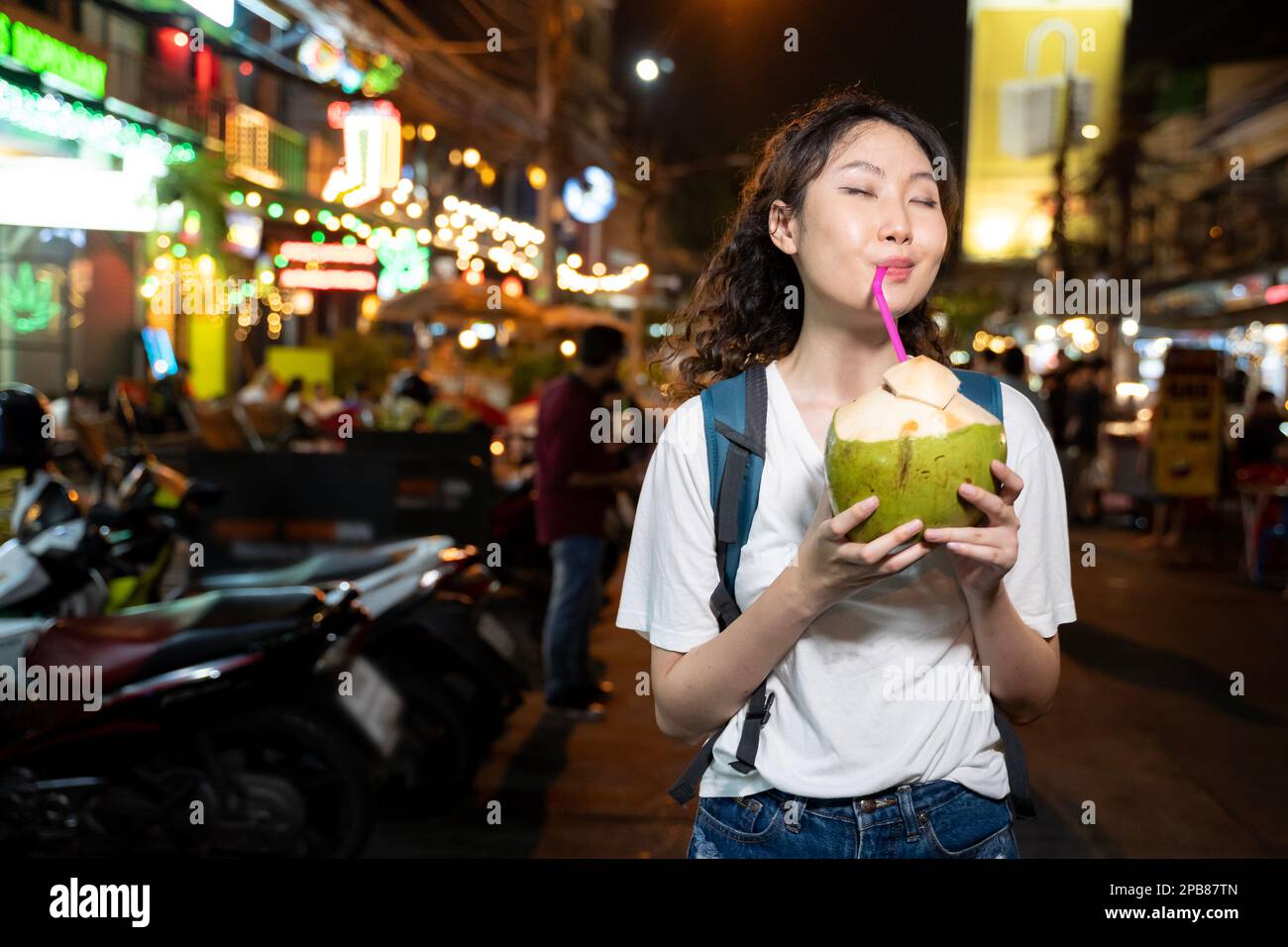 Portrait of happy relaxing Asian solo hipster traveller holding a ...