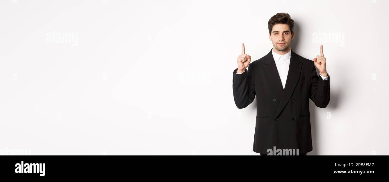 Image of confident and handsome man in formal suit, pointing fingers up ...