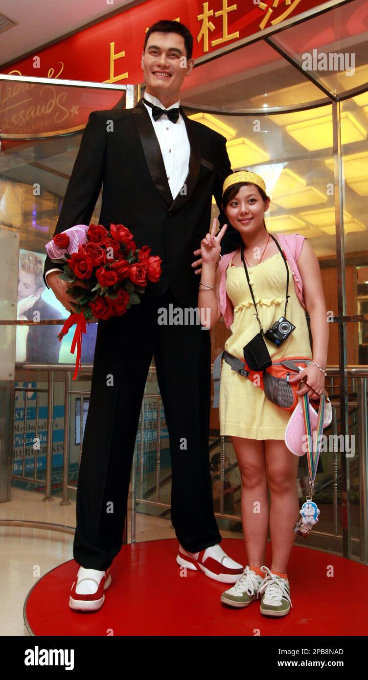 A tourist poses with the wax figure of Yao Ming dressed in a wedding ...