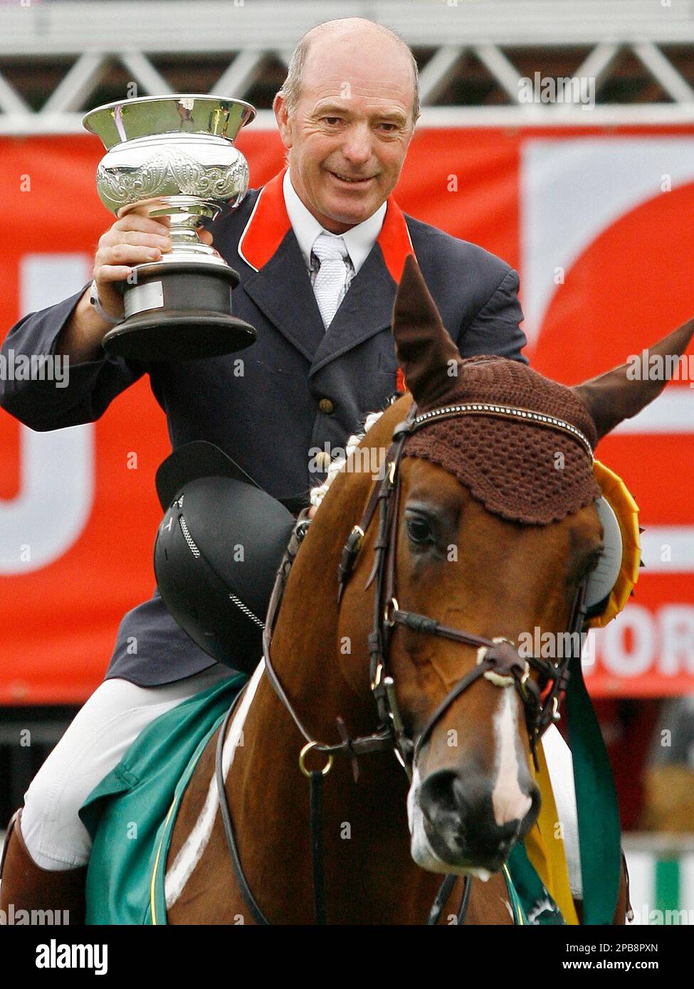 Great Britain's John Whitaker holds up a trophy after winning the 1.55 ...