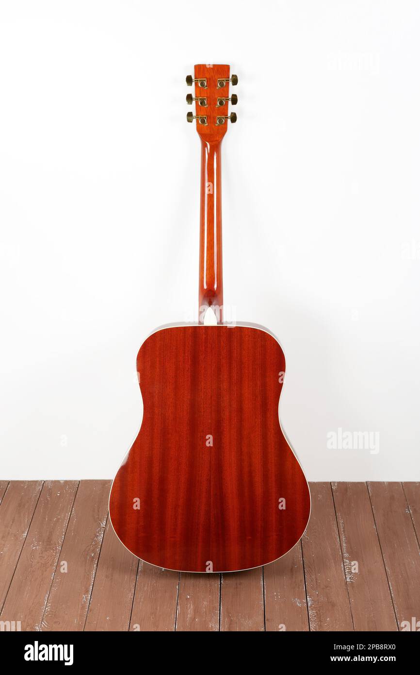 Musical instrument - back view classic acoustic guitar on a white wall ...
