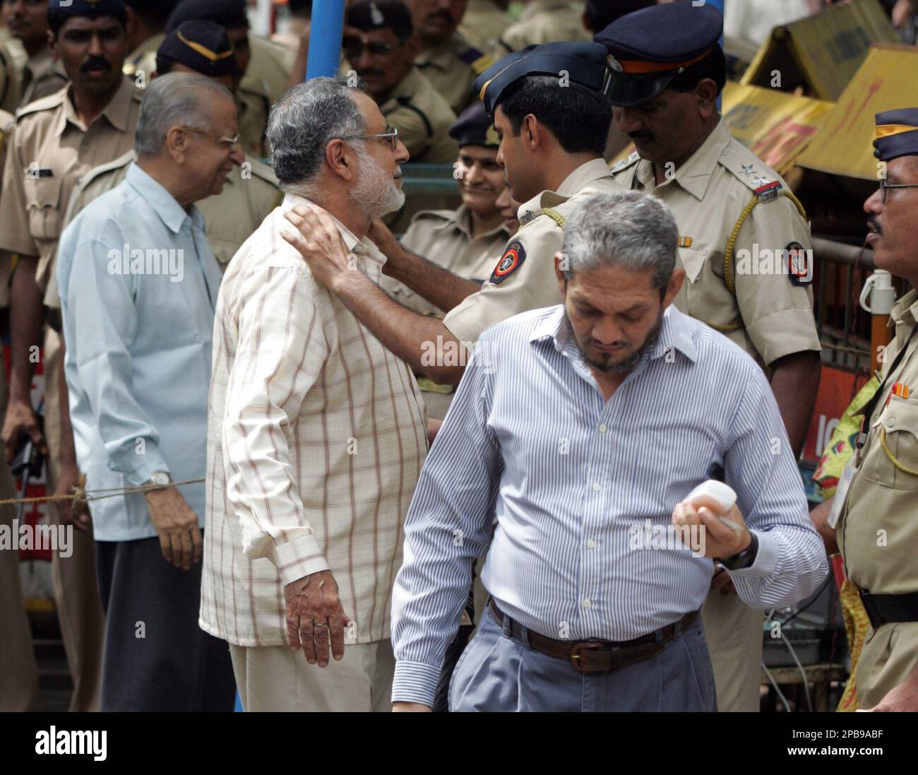 Yusuf Nulwala, front, walks away as policemen frisk Rusi Mulla, center ...